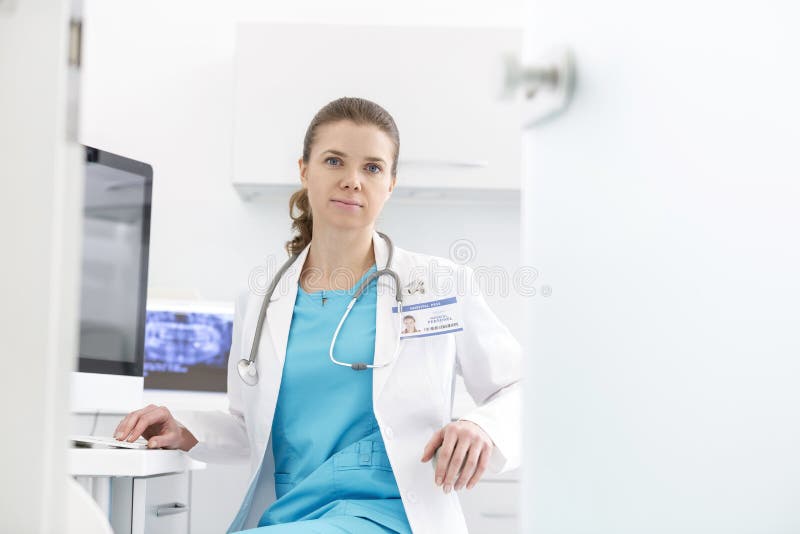 Confident Doctor Sitting at Computer Desk in Dental Clinic Stock Photo ...