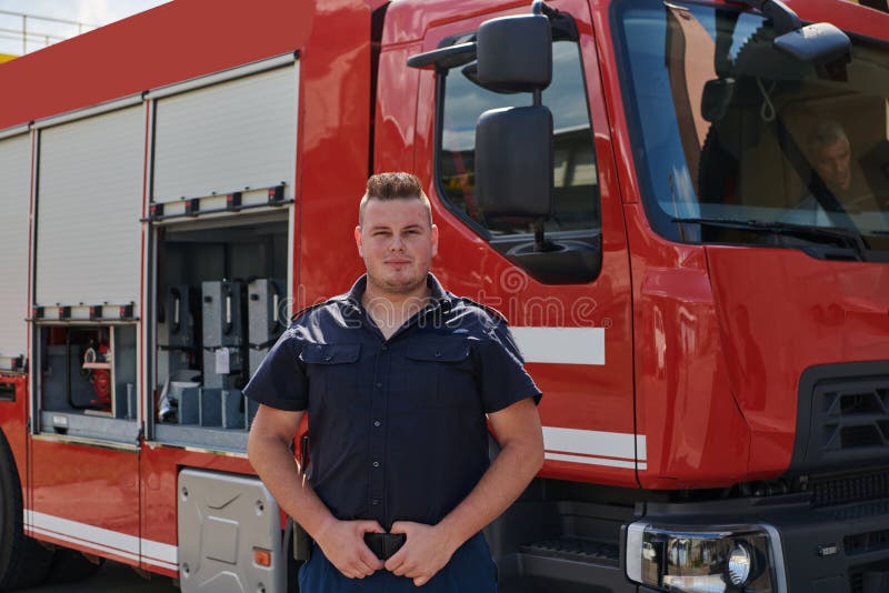 A Confident Firefighter Strikes a Pose in Front of a Modern Firetruck ...