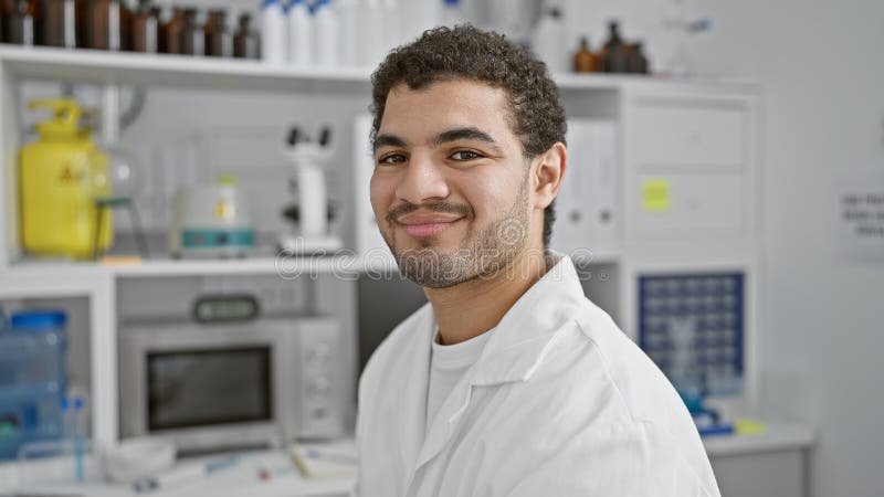 A Confident Man with a Beard in a Lab Coat Stands in a Well-equipped ...
