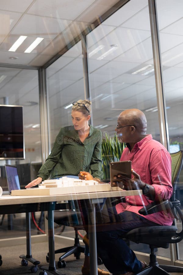 Confident Multiracial Architects Discussing Over Model at Desk in ...