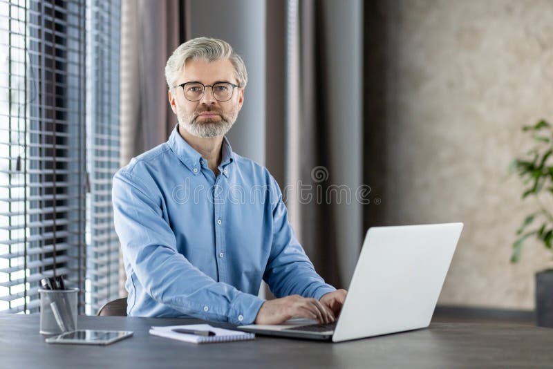 Confident Professional Man Working on Laptop in Modern Office Setting ...