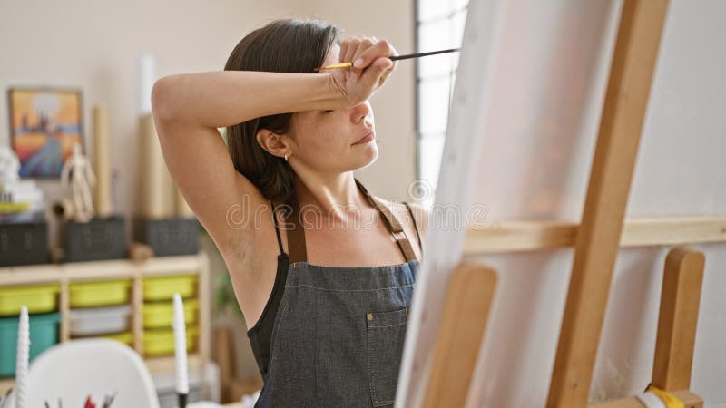 Confident, Smiling Young Hispanic Woman Sweating while Drawing ...