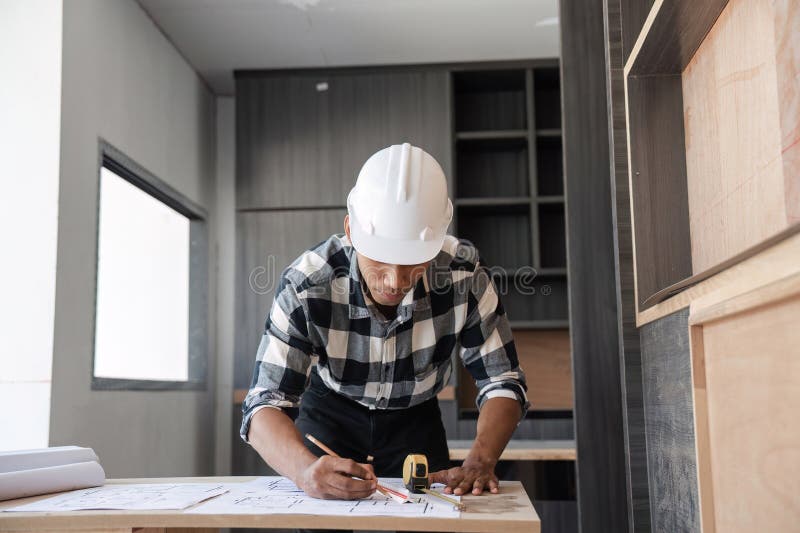 Confident Young Engineer Planning Work with Blueprints in Modern Office ...