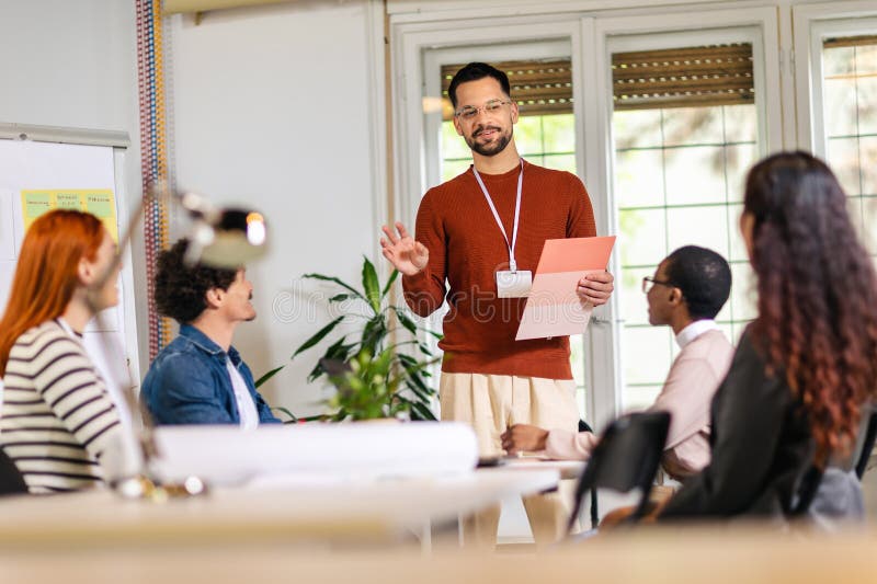 Young Team Leader Giving a Presentation To a Group of Young Colleagues ...