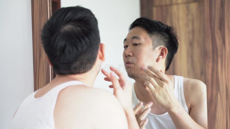 Puzzled Asian Man Checking Acne Problems while Looking in Mirror Stock ...