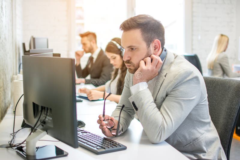 Businessman with Headset and Eyeglasseslooking at Computer in Office ...