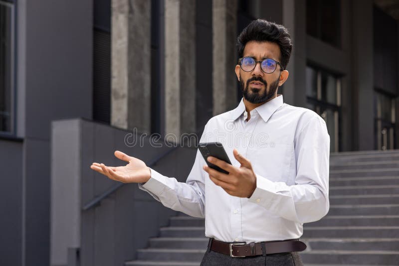 Confused Businessman with Smartphone Gesturing with Hand Outdoors ...
