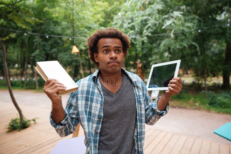 Confused Man Holding Book and Tablet Outdoors Stock Image - Image of ...