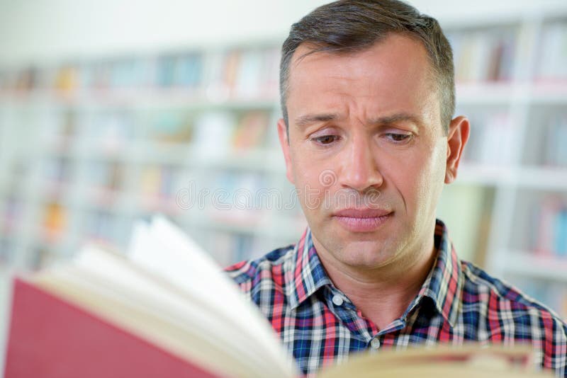 Confused man reading book stock photo. Image of story - 319216036
