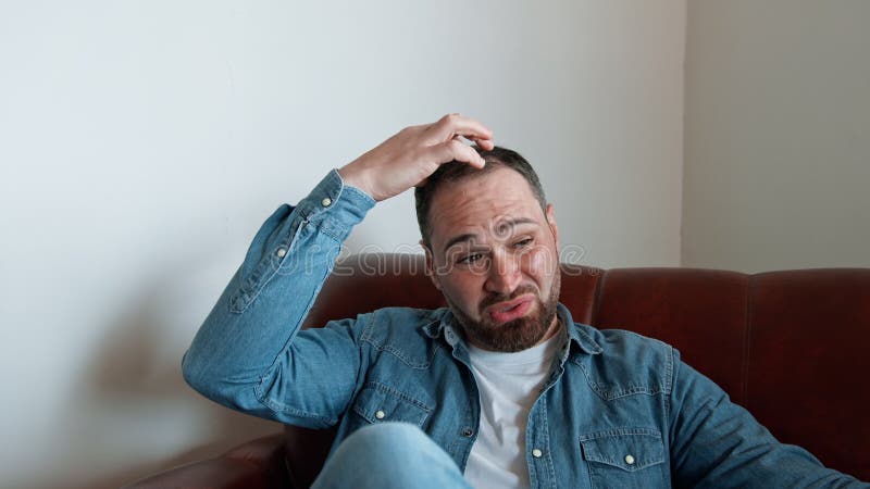 Confused Man Scratching His Head on the Sofa Stock Footage - Video of ...