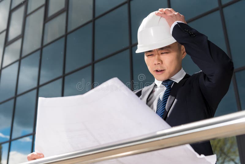 Confused Professional Architect in Hard Hat Looking at Blueprint Stock ...