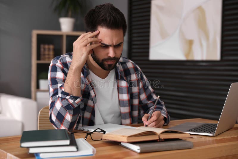 Confused Young Man Writing Down Notes during Webinar at Table in Room ...