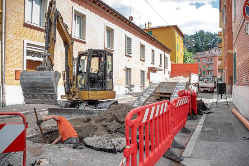 Construction Area with Operator Digging with Red Safety Barriers and ...