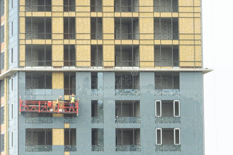 Construction Cradle on a Building at a Height with Workers. Work at ... Construction Cradle on a Building at a Height with Workers. Work at ...