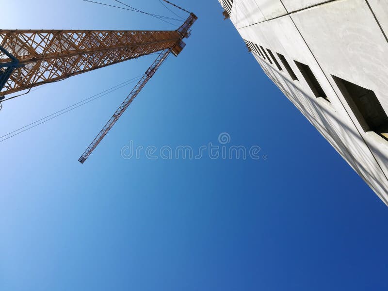 Construction Crane Rises Above the Building. Bottom Up View on Blue Sky ...