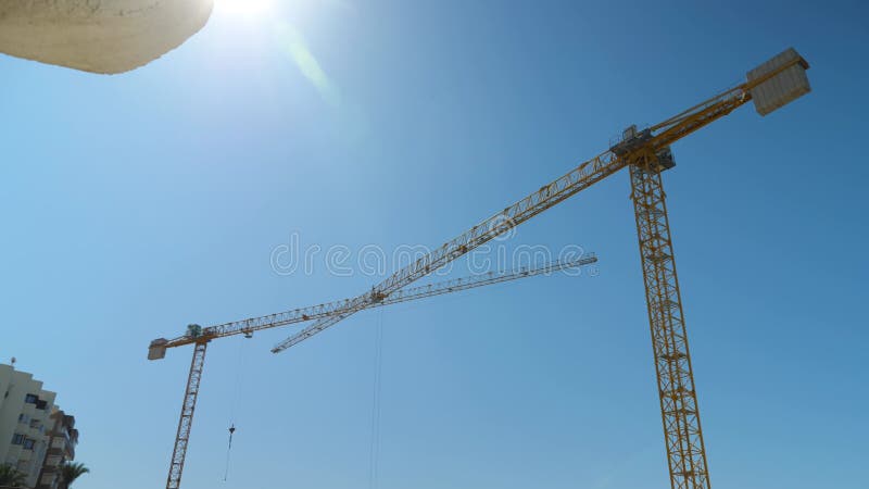 Construction Cranes Against the Blue Sky and Bright Sun. the Concept of ...