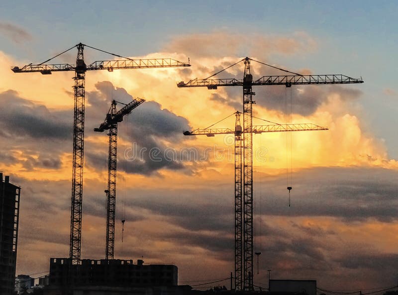 Construction Cranes on the Background of the Sunset Sky. Bright Clouds ...