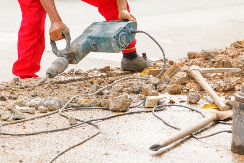 Construction Drilling Repair Worker on Road Surface with Heavy Duty ...