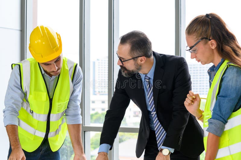 Construction Engineer and Architect in Vest and Helmet Discussing ...