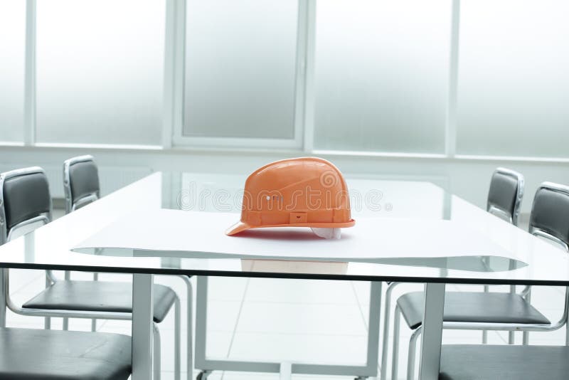 Construction Hard Hat and Blueprints on Glass Table in Office Space ...