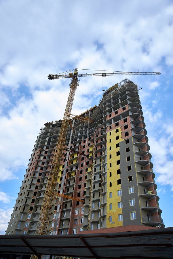 Construction of a High-rise Building by Tower Cranes Against a Blue Sky ...
