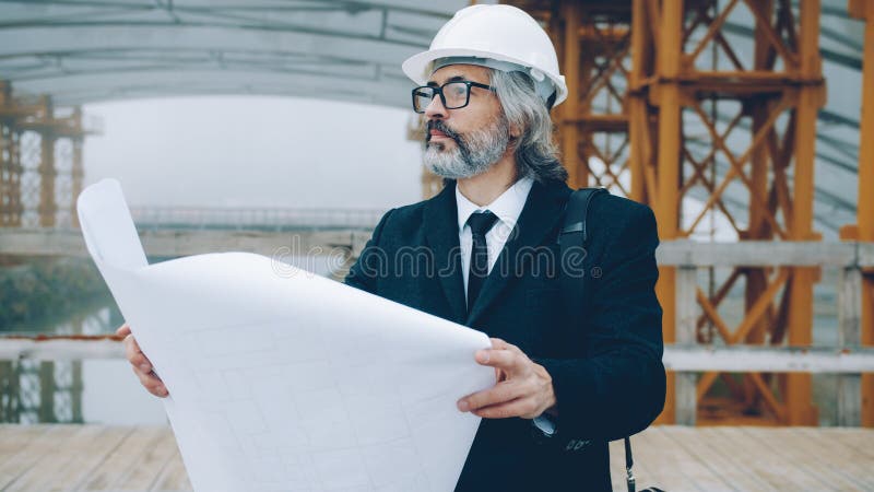Construction Inspector Studying Blueprint and Looking Around Building ...