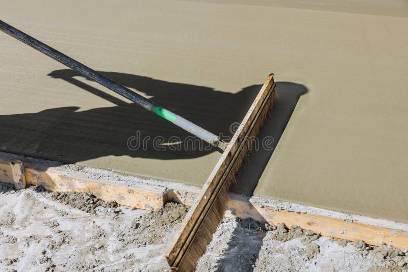 A Construction Laborer Uses a Broom To Brush Fresh Wet Concrete Causing ...
