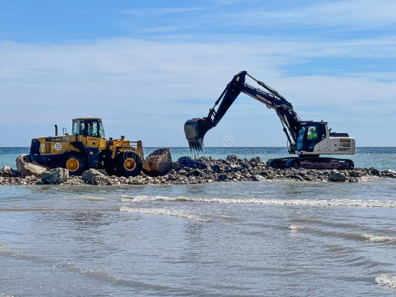 Construction Machinery Working on Coastal Rock Formation at Beach Site ...