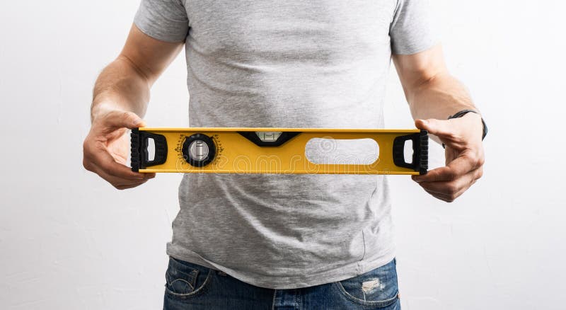 Construction: a Man Holds a Yellow Building Level in His Hands. Stock ...