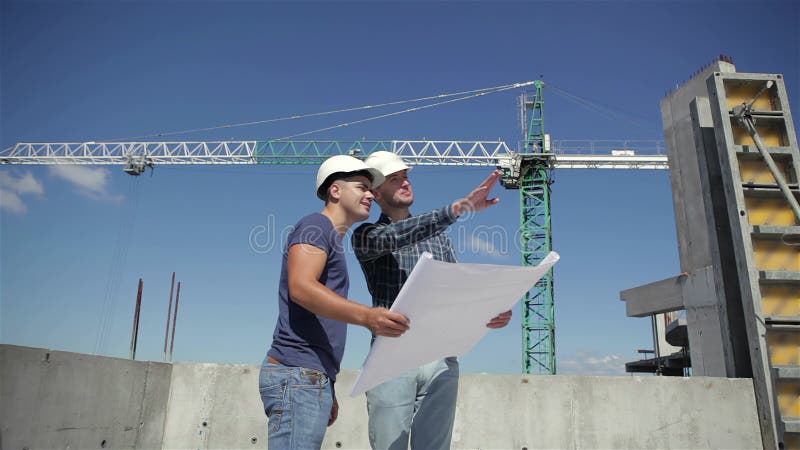 Construction Manager Points at the Plan of Building Under Construction ...