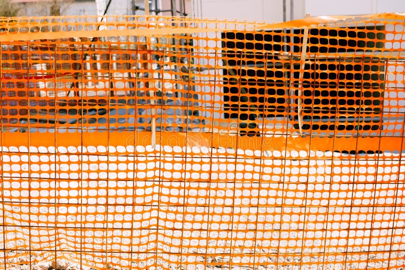 Construction Materials Lie Behind an Orange Construction Grid in a ...
