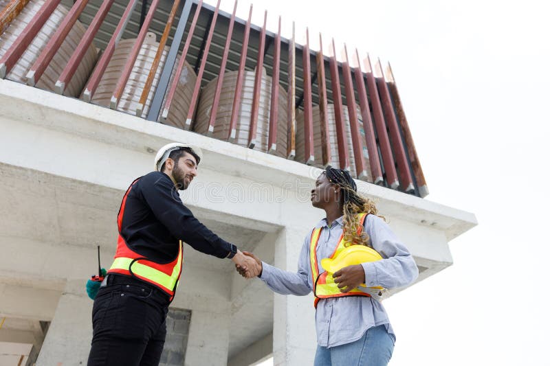 Construction Professionals Shaking Hands at a Building Site, Symbolizing Teamwork, Partnership ...