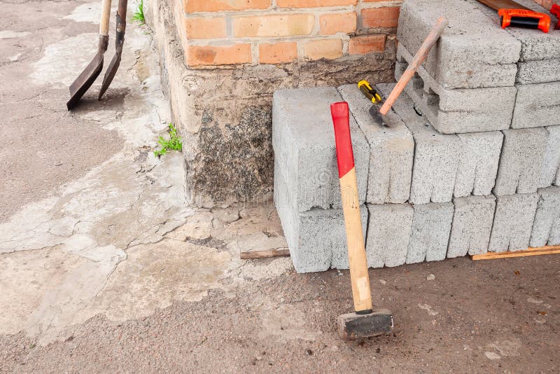 Construction Scene Featuring a Sledgehammer, Blocks, and Trowels, by a ...