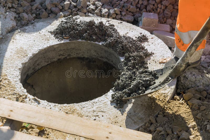 At a Construction Site, a Cast-iron Sewer Hatch is Being Installed on a ...
