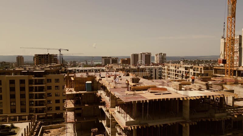 Construction Site with Crane Lifting Wooden Boards at Sunset. Workers ...