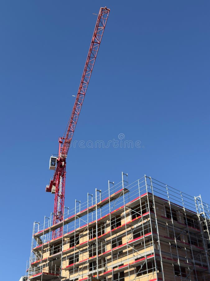 A Construction Site with a Red Tower Crane Lifting Materials. Editorial ...
