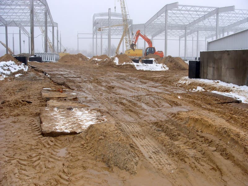 Construction Site with Steel Framework and Muddy Ground, Machinery in ...