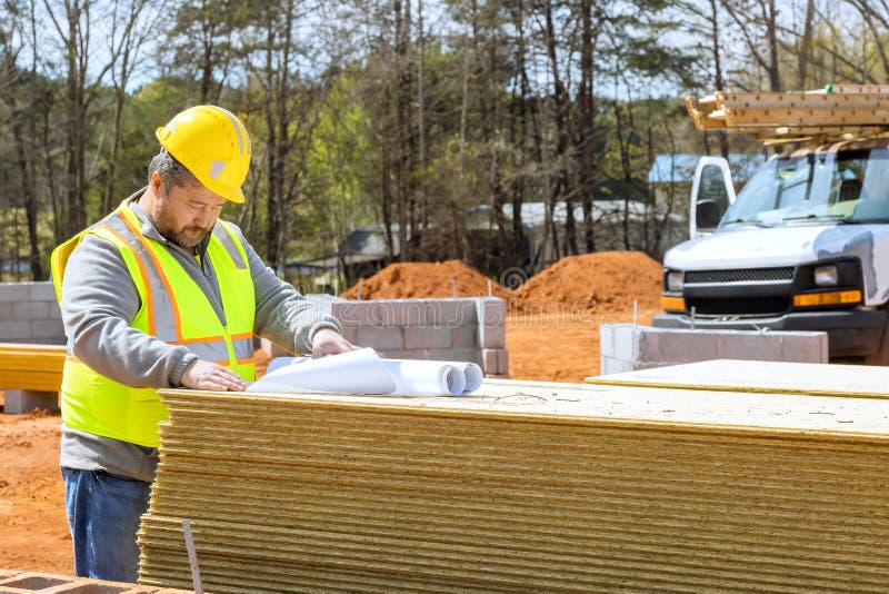 Construction Supervisor Worker Reviewing Plans at Job Site during ...