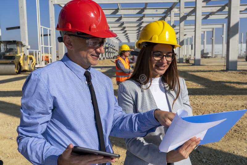 Construction Supervisor and Young Female Architect Checking Project Documents at Construction ...
