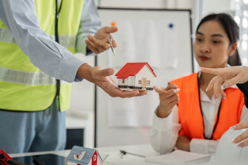 Construction Team Discussing Project Plans with a Miniature House Model ...