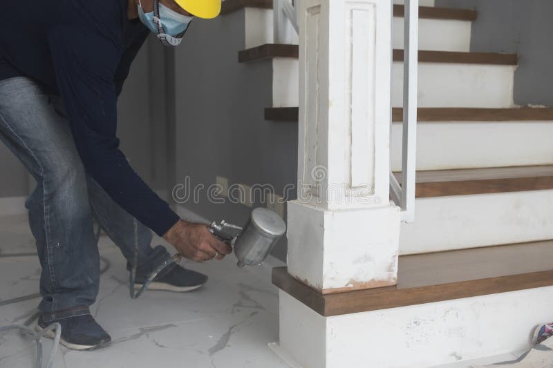 A Construction Worker Applies Varnish on the Stairs. Using an Airbrush ...