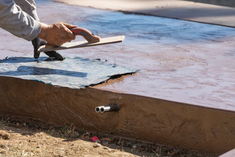 Construction Worker Applying Pressure To Texture Template on Wet Cement ...