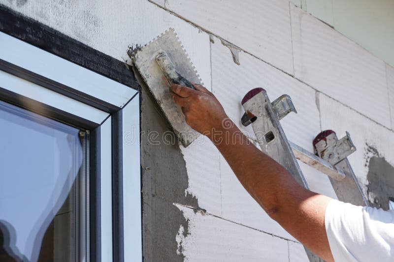 Construction Worker Applying Top Layer of Plaster Next To Newly ...