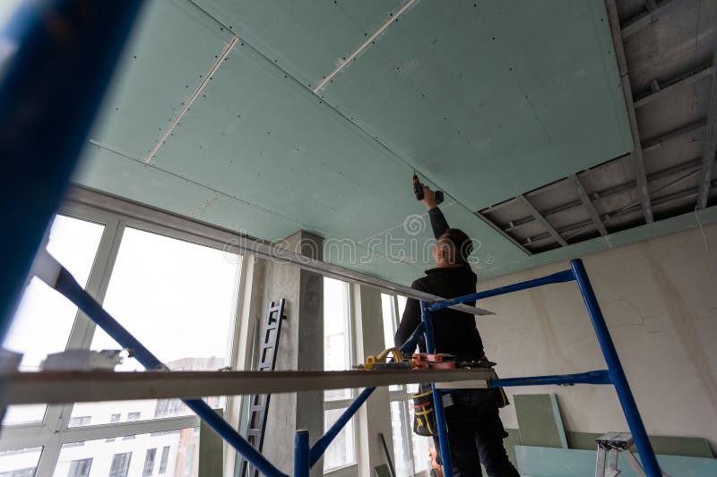 Construction Worker Assemble a Suspended Ceiling with Drywall and ...