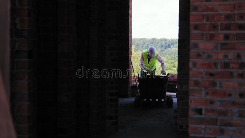 Construction Worker Bending Over at a Building Site. a Construction ...