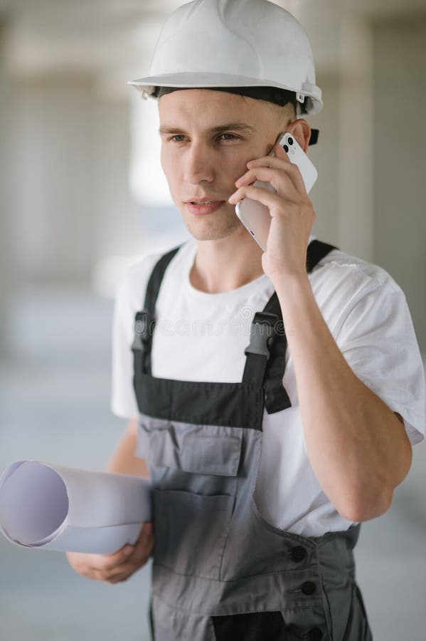 A Construction Worker with Blueprint Talking on the Phone.Young Worker ...