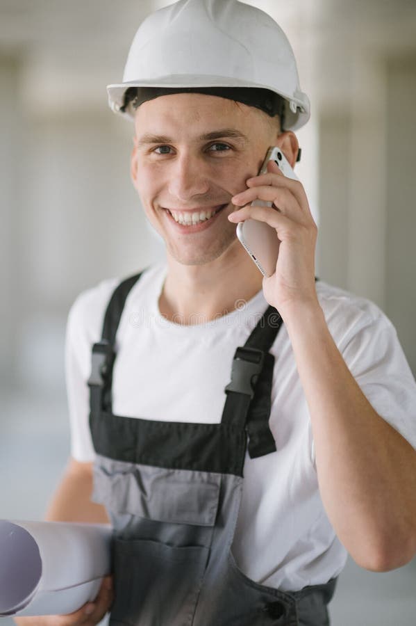 A Construction Worker with Blueprint Talking on the Phone.Young Worker ...