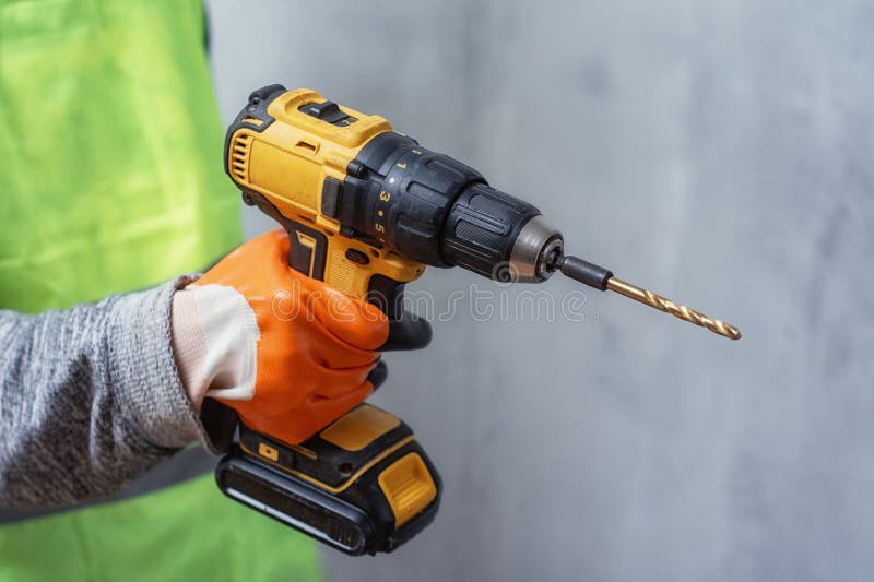 A Construction Worker in a Bright Safety Vest Holds a Cordless Drill ...