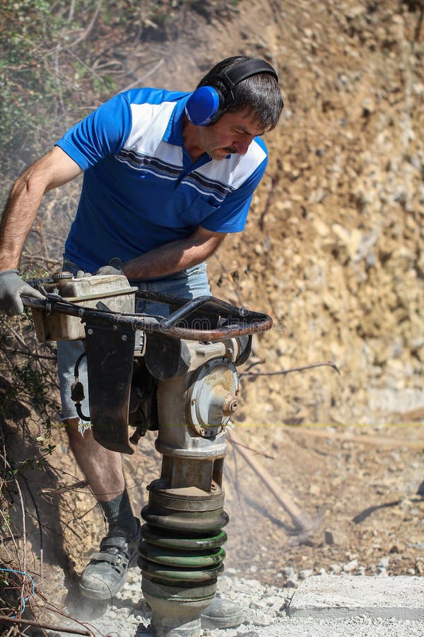 Construction Worker Compacting Soil Using Compactor. Work with Tamping ...
