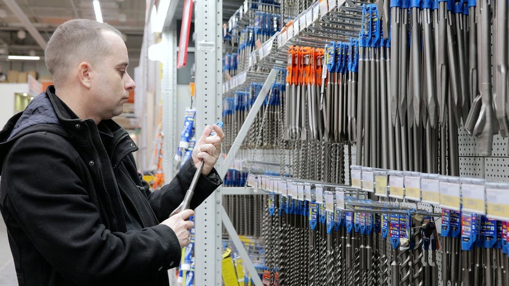 Construction Worker Comparing Drill Bit Options in Hardware Store ...